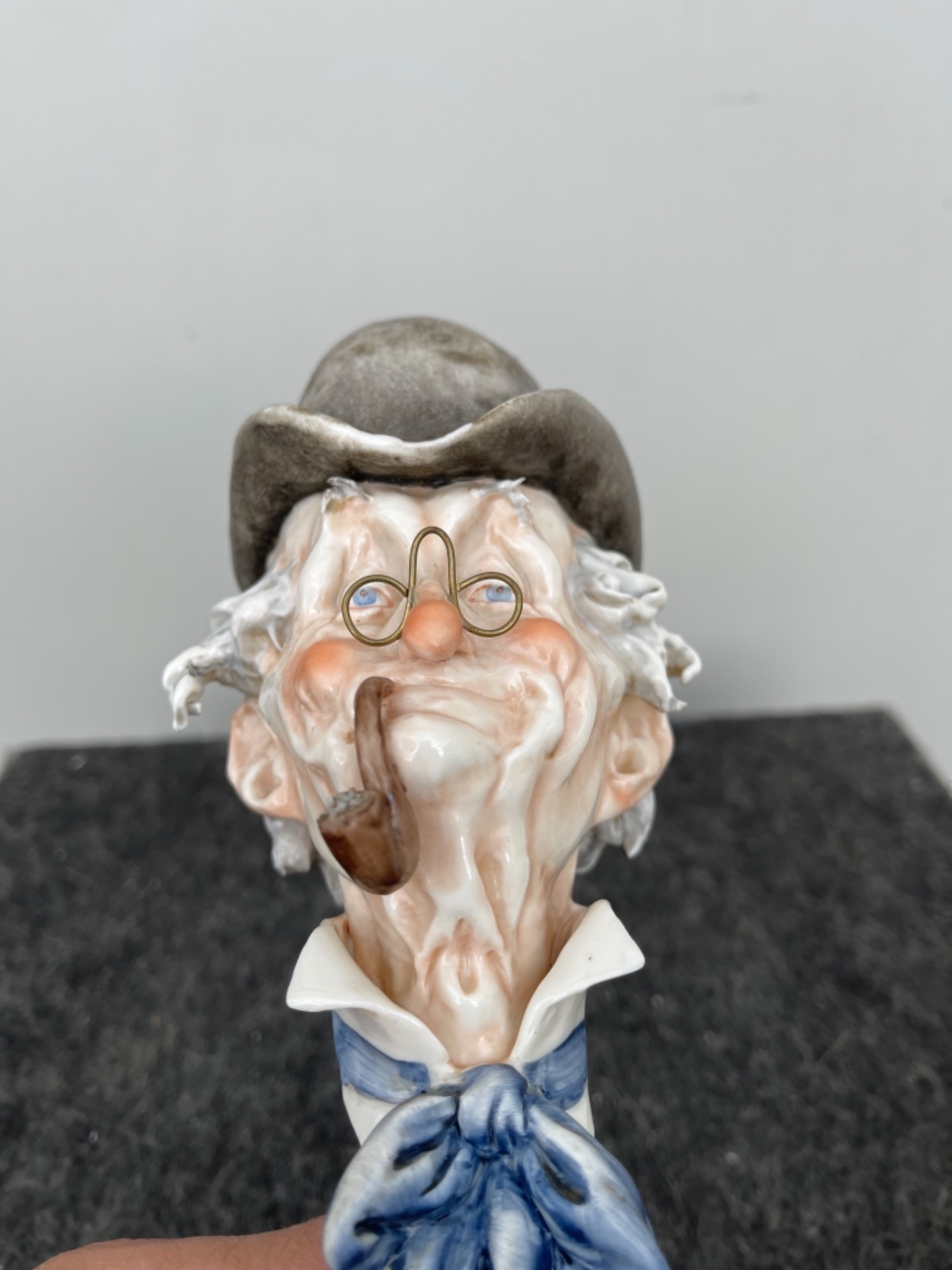 Polychrome porcelain sculpture depicting a man's head with a hat and ...