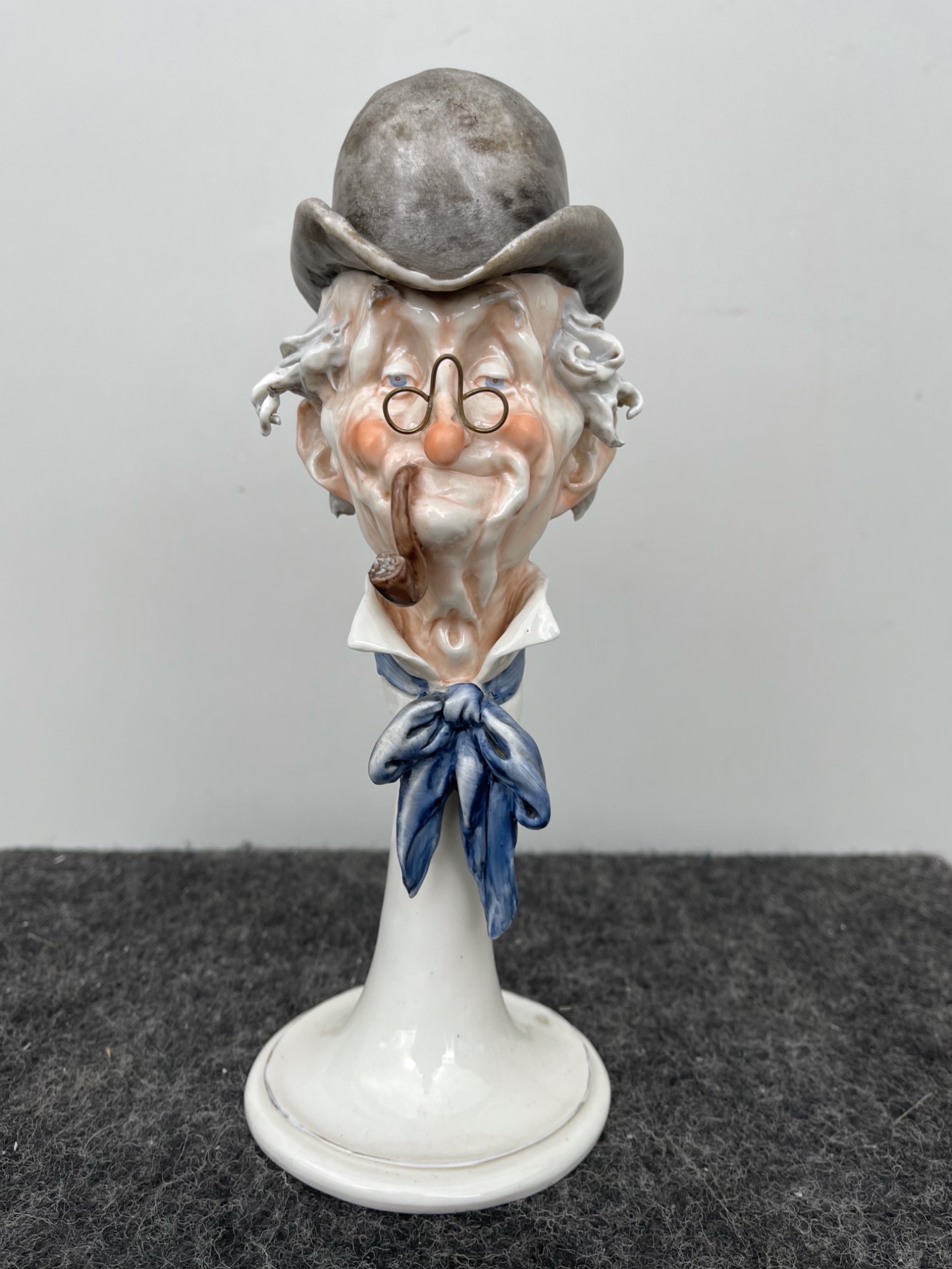 Polychrome porcelain sculpture depicting a man's head with a hat and ...