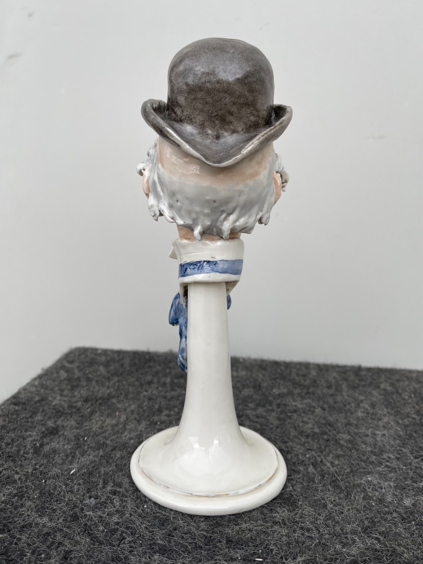 Polychrome porcelain sculpture depicting a man's head with a hat and ...